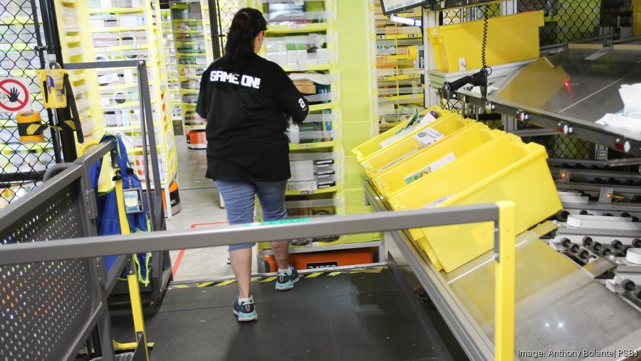 Totes carrying merchandise are transported atop conveyors as seen ...