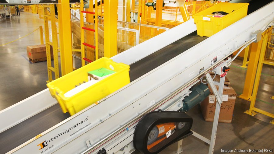 Totes carrying merchandise are transported atop conveyors as seen ...